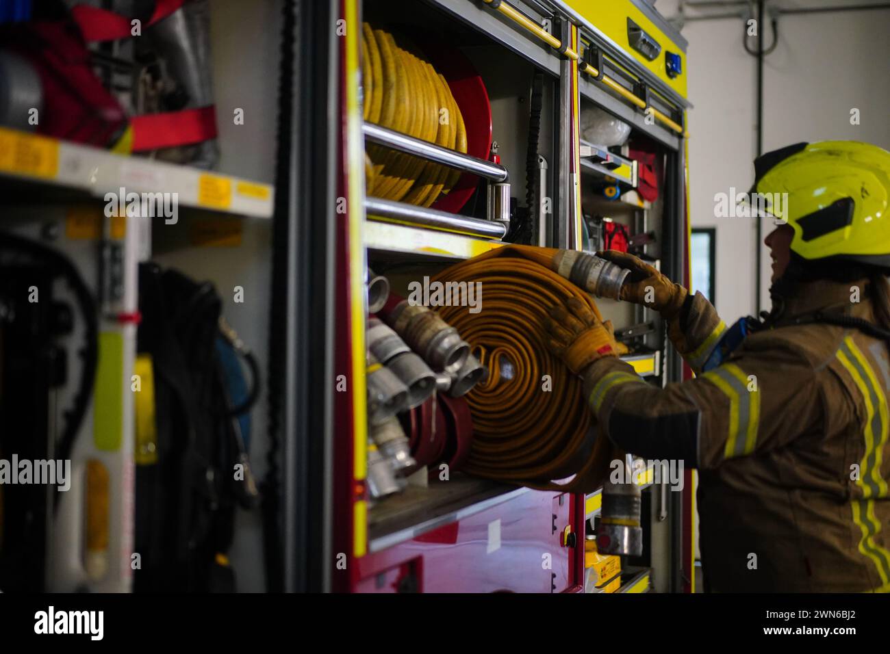 A female firefighter prepares equipment on a fire engine during a ...