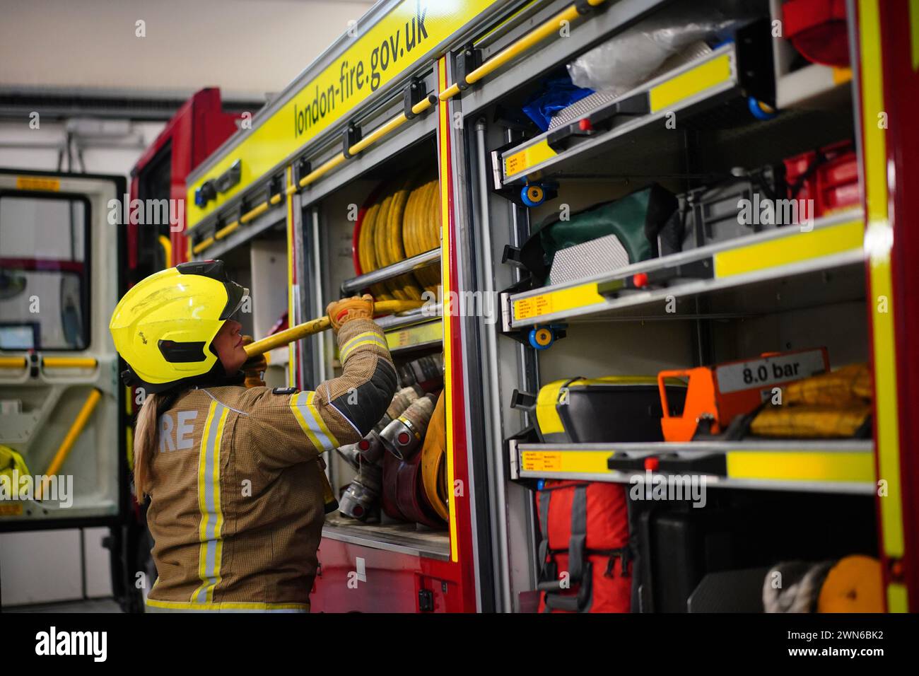 A female firefighter prepares equipment on a fire engine during a ...