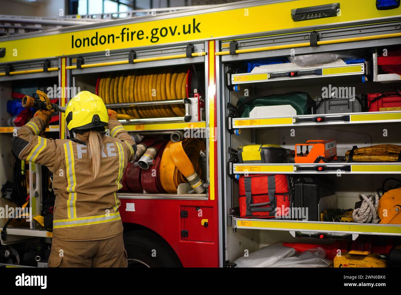 A female firefighter prepares equipment on a fire engine during a ...