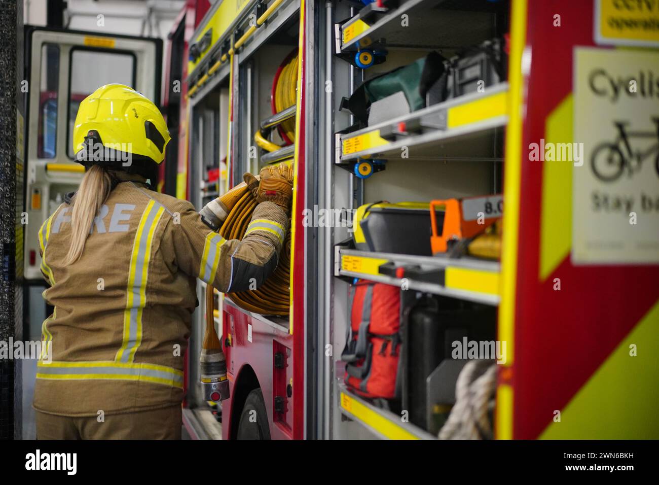 A female firefighter prepares equipment on a fire engine during a ...