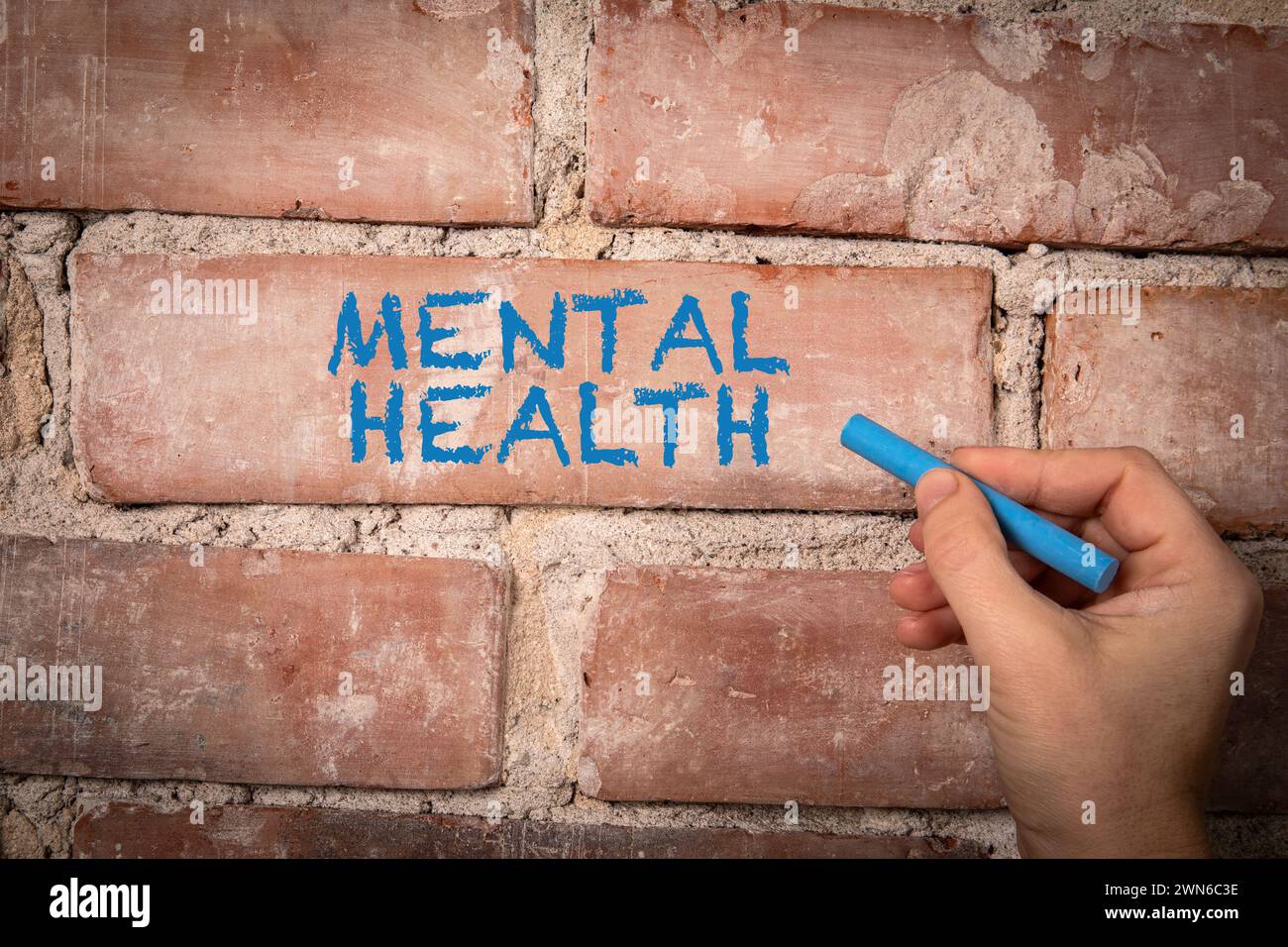 MENTAL HEALTH. Text written with purple chalk on a red brick background ...