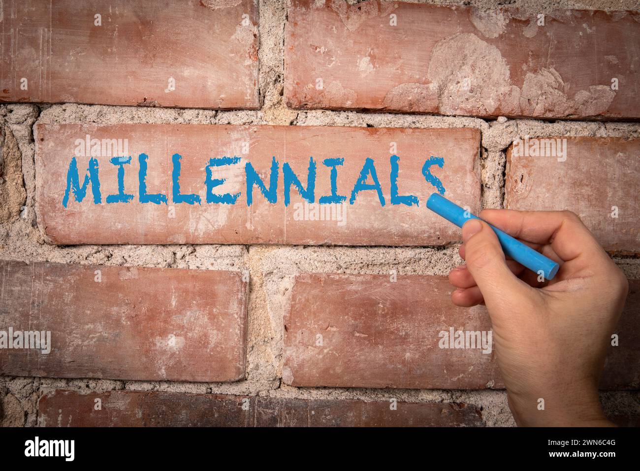 Millennials. Text written with purple chalk on a red brick background ...