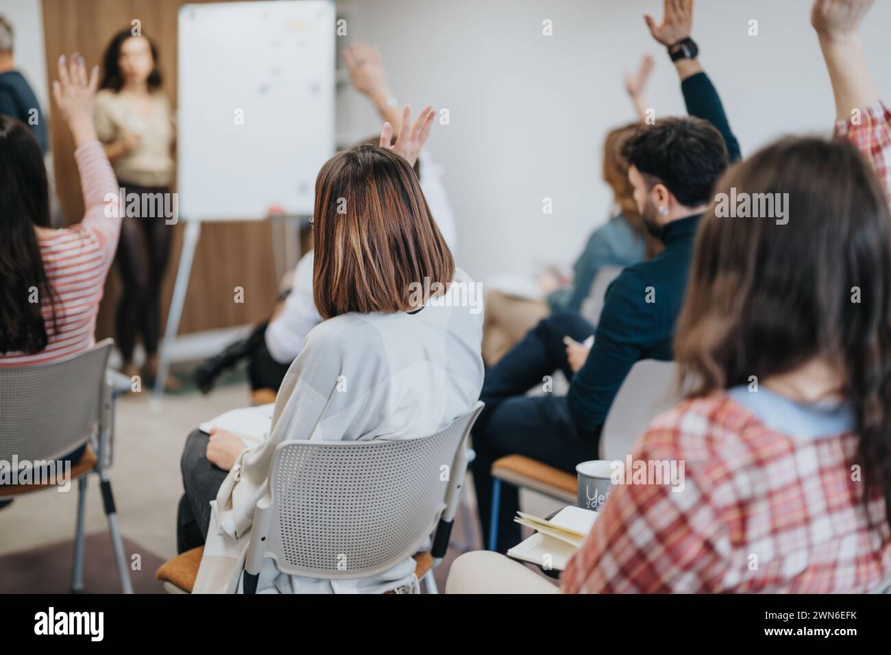Engaged audience raising hands in a business workshop with female ...