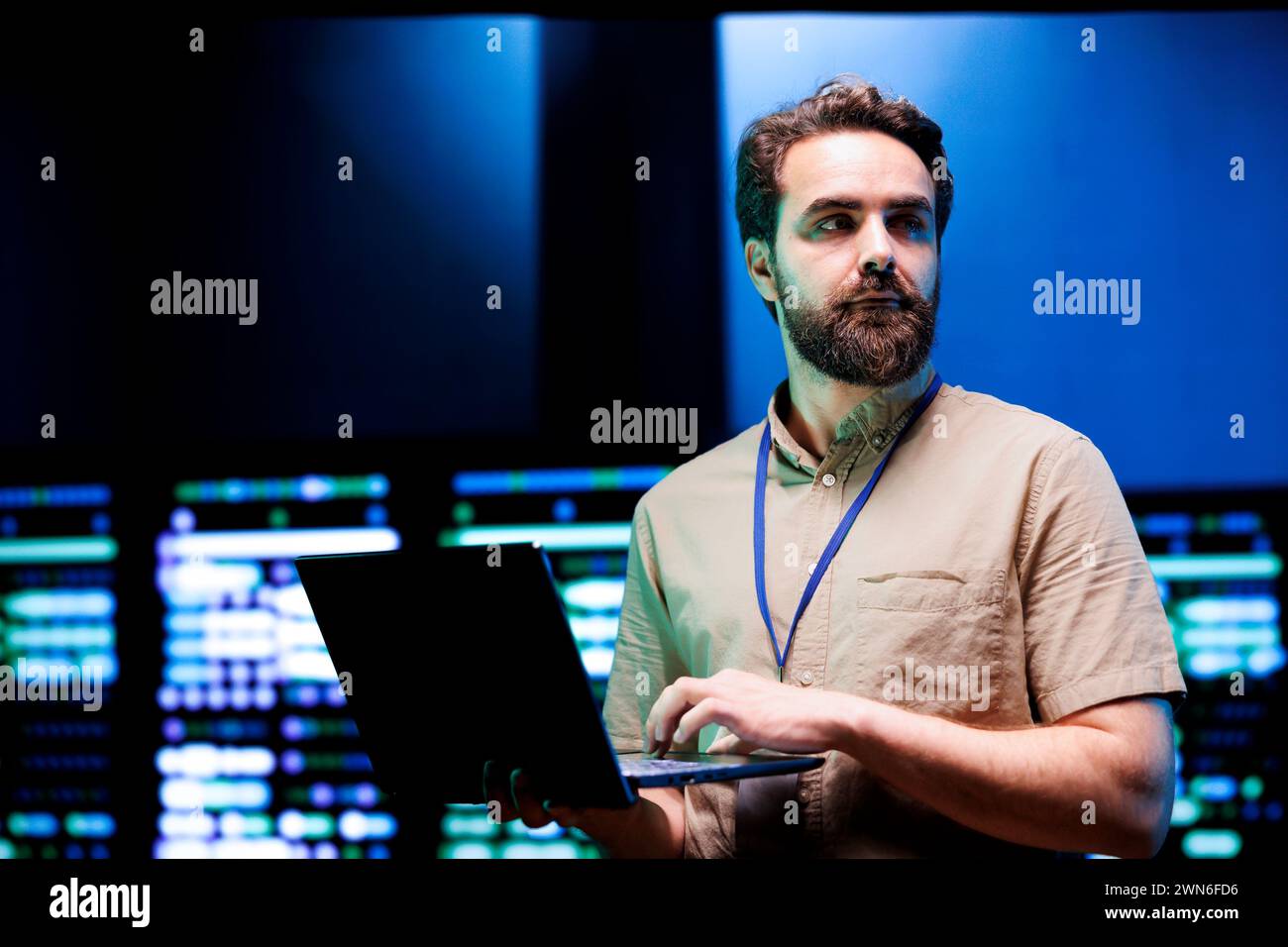 Employee using laptop to do assessments of server farm rackmounts doing ...