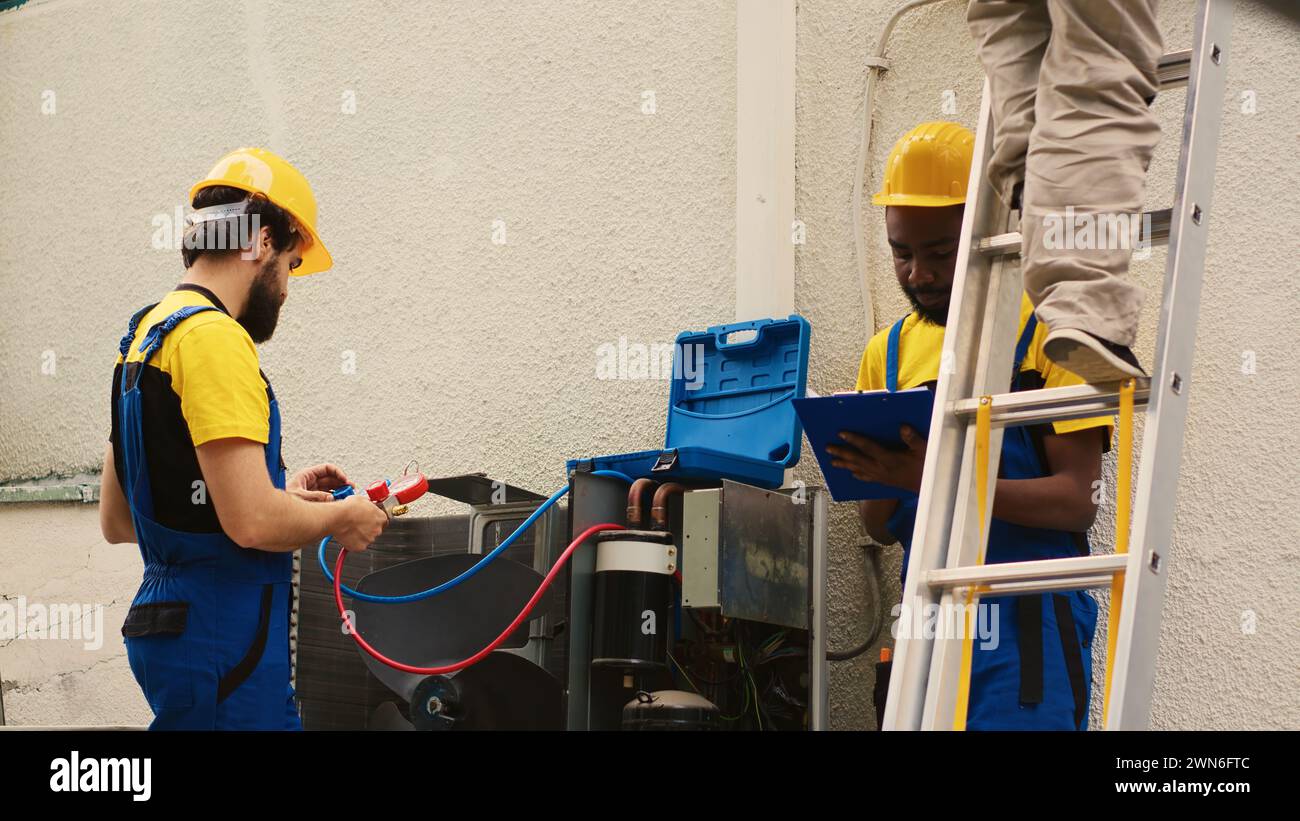 Specialists measuring freon levels in HVAC system with pressure ...