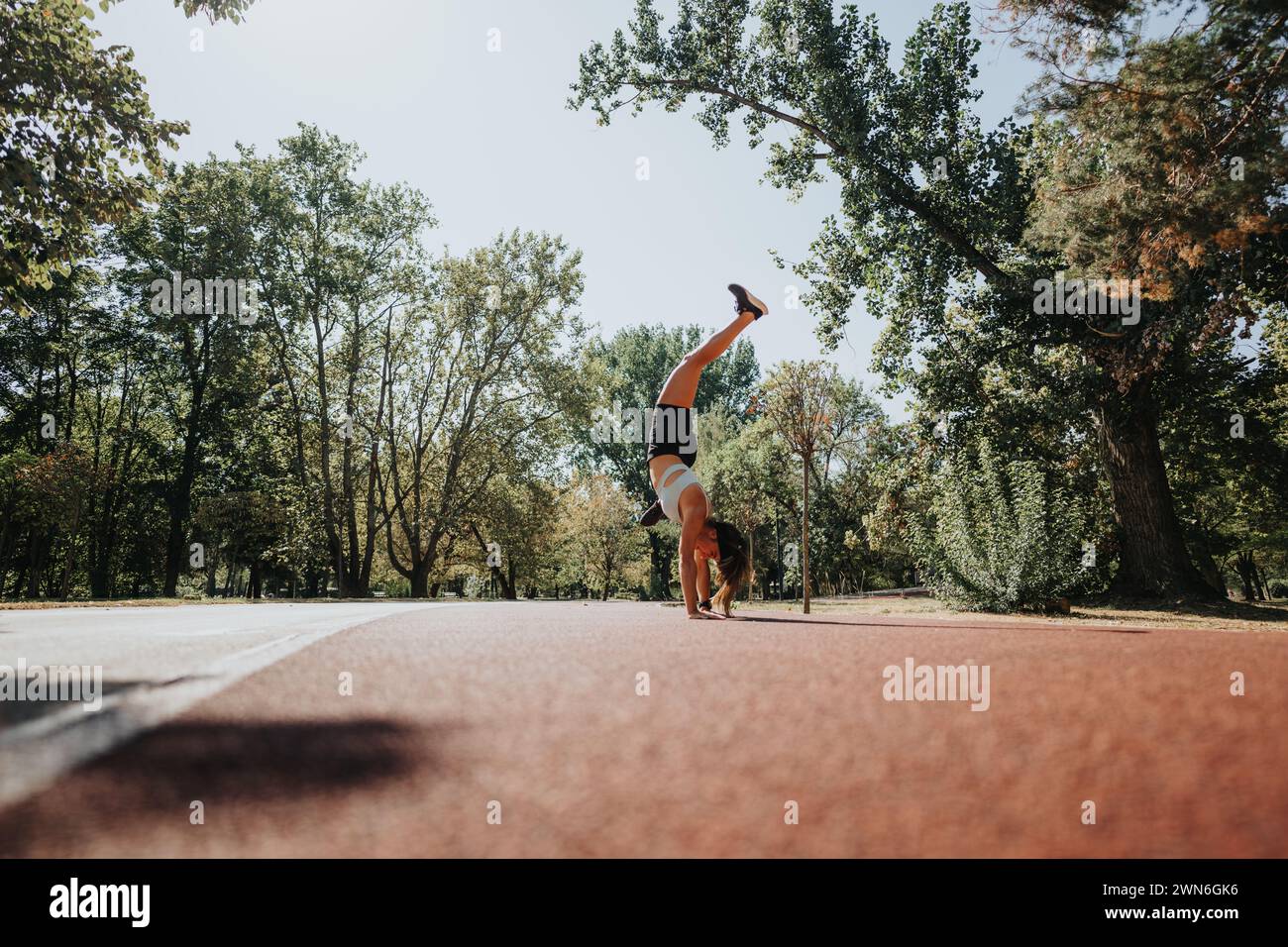 Two women perform cartwheels in a sunny park, enjoying an active ...