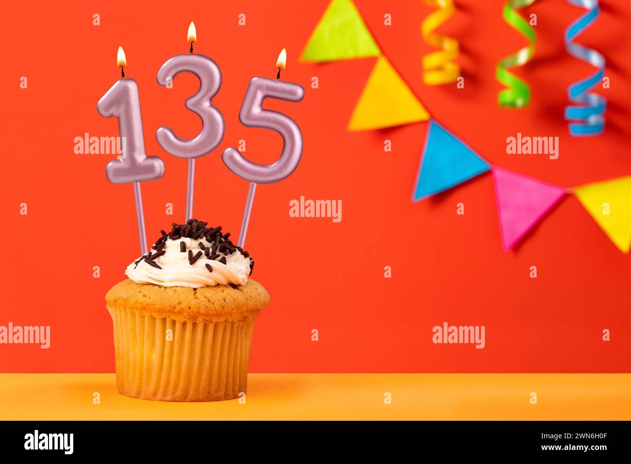 Birthday cupcake with number 135 candle - Sparkling orange background ...