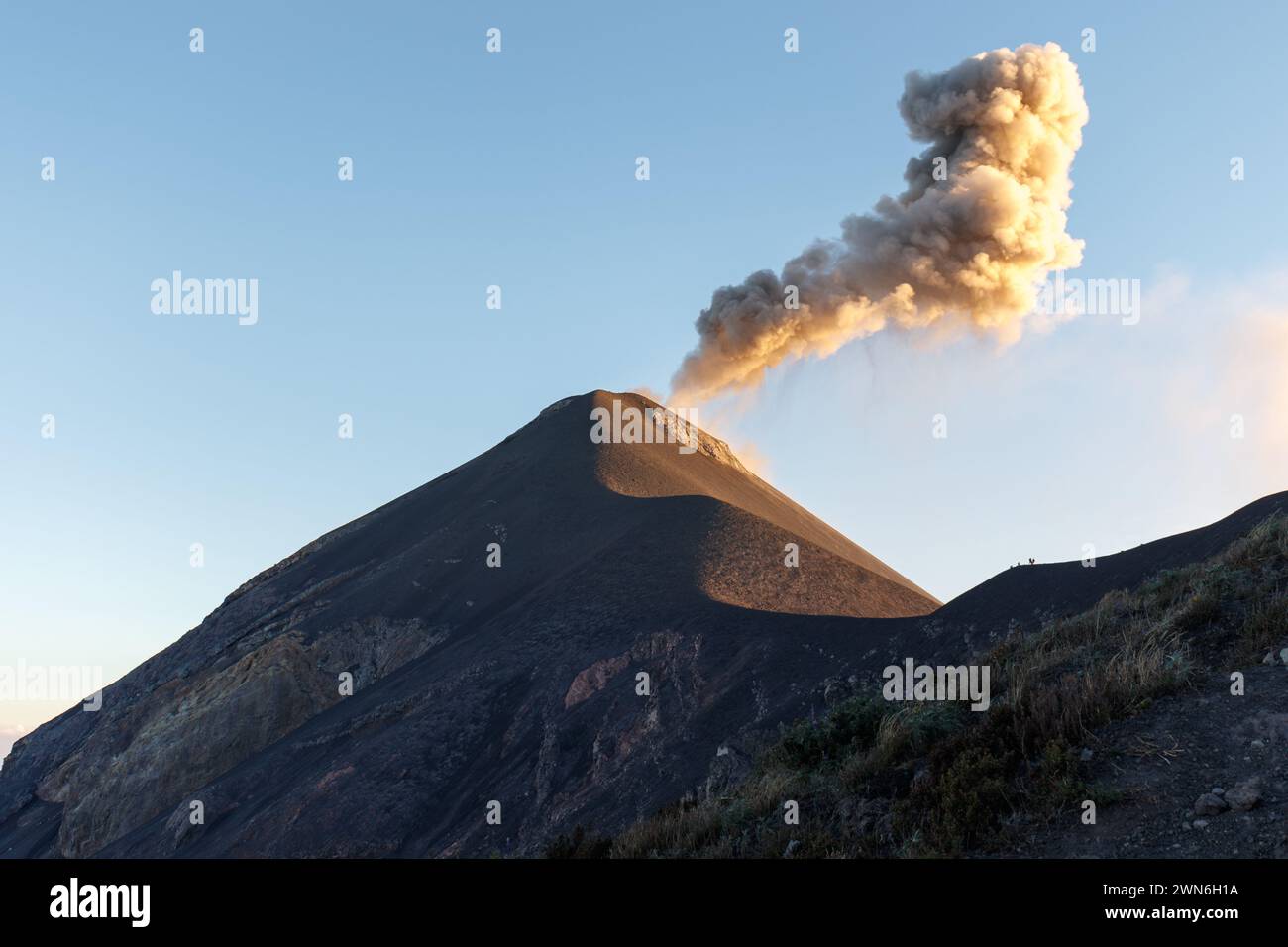 Close up of volcano erupting with orange smoke column at sunrise, clear ...