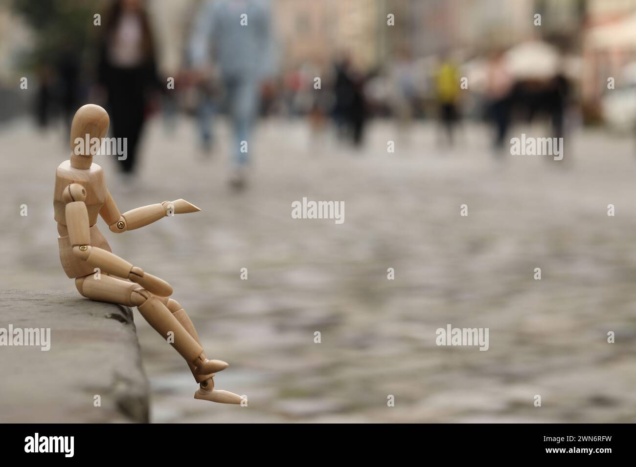 Wooden human figure sitting on curb outdoors, space for text Stock ...