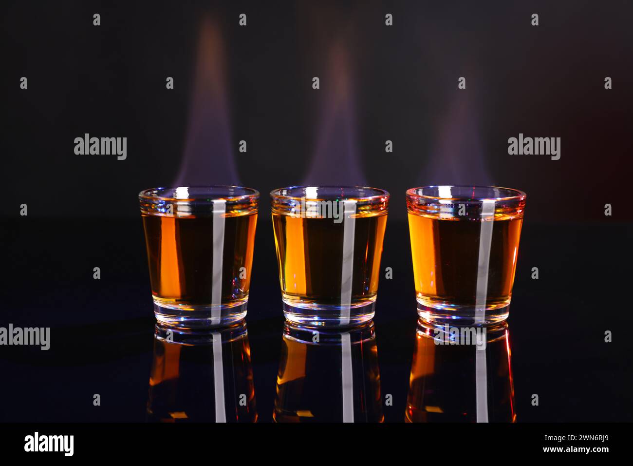 Flaming alcohol drink in shot glasses on mirror surface Stock Photo - Alamy