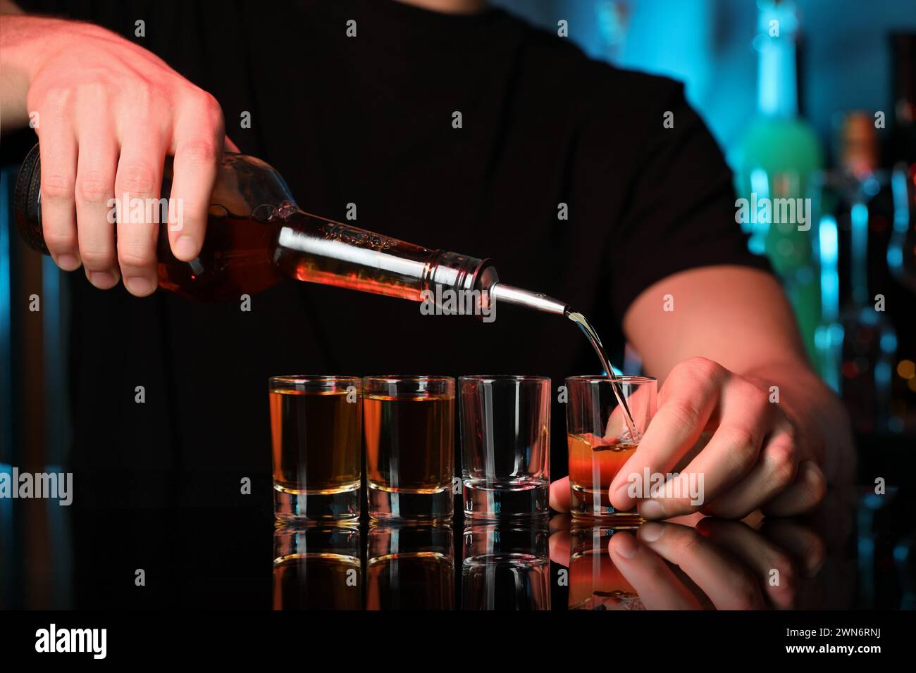 Bartender pouring alcohol drink into shot glass at mirror counter in bar, closeup Stock Photo ...