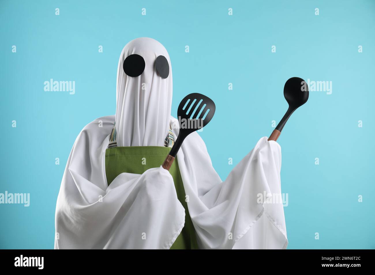 Woman in ghost costume and apron with kitchen set on light blue ...