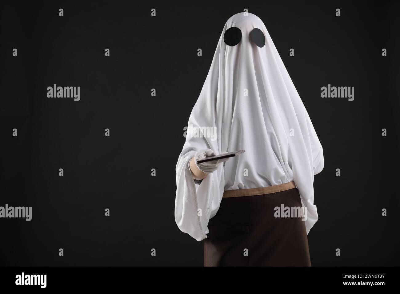 Creepy ghost. Waiter in white sheet and apron with receipt on black ...