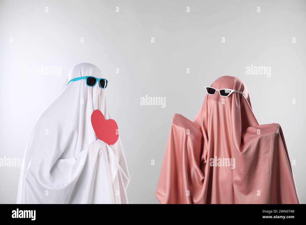 Cute ghosts. Couple in color sheets and sunglasses with red heart on ...