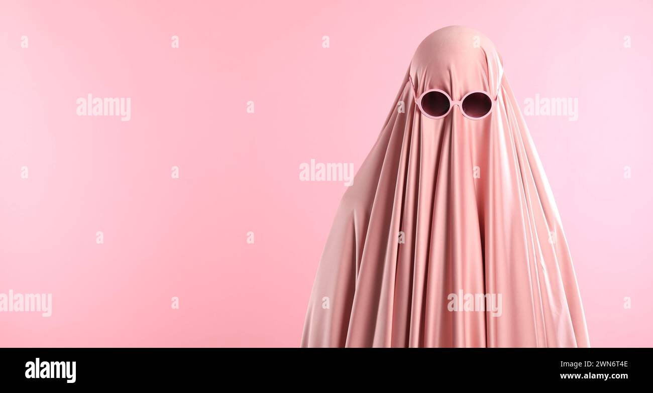Glamorous ghost. Woman in sheet with sunglasses on pink background ...
