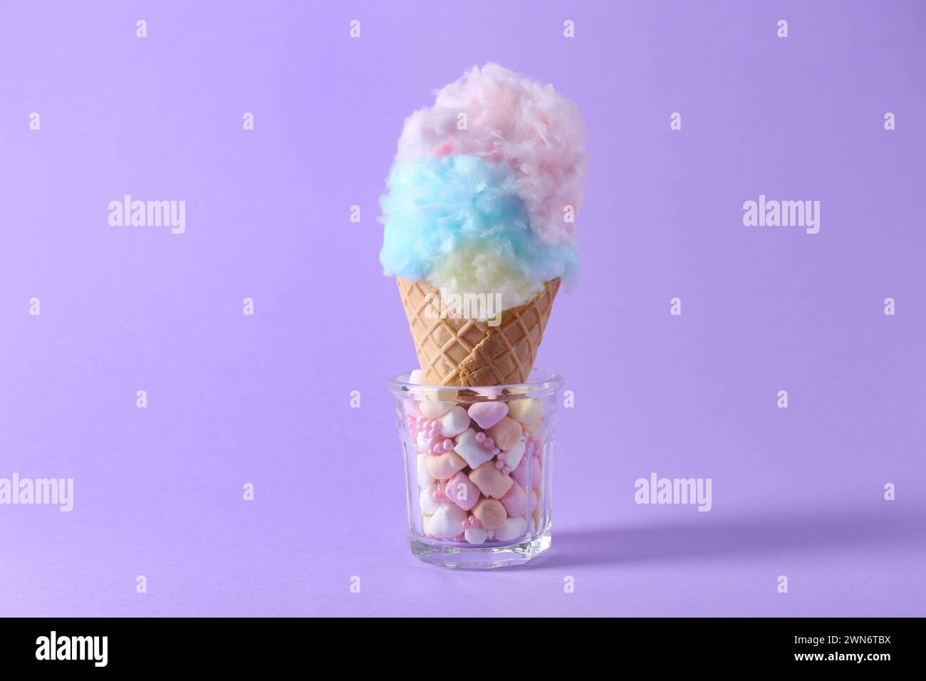 Sweet cotton candy in waffle cone on purple background Stock Photo - Alamy