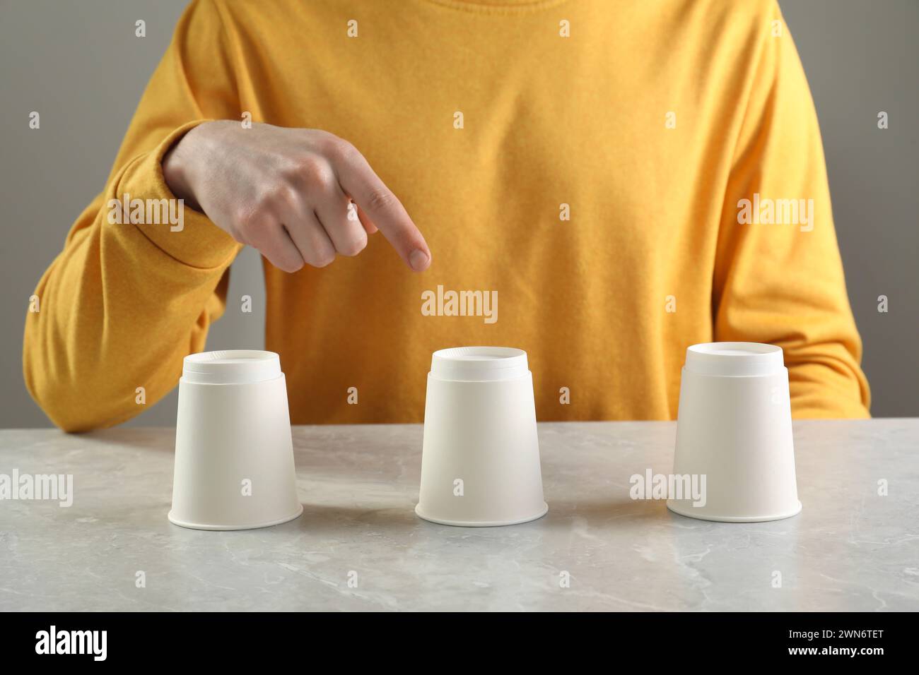 Man playing shell game at light marble table, closeup Stock Photo - Alamy