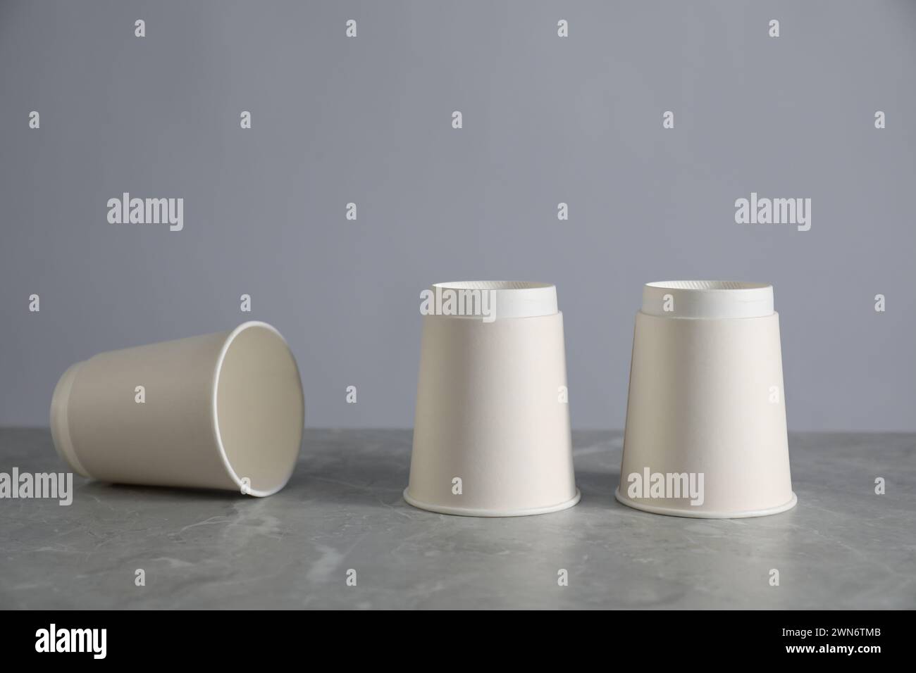 Shell game. Three paper cups on grey marble table Stock Photo - Alamy