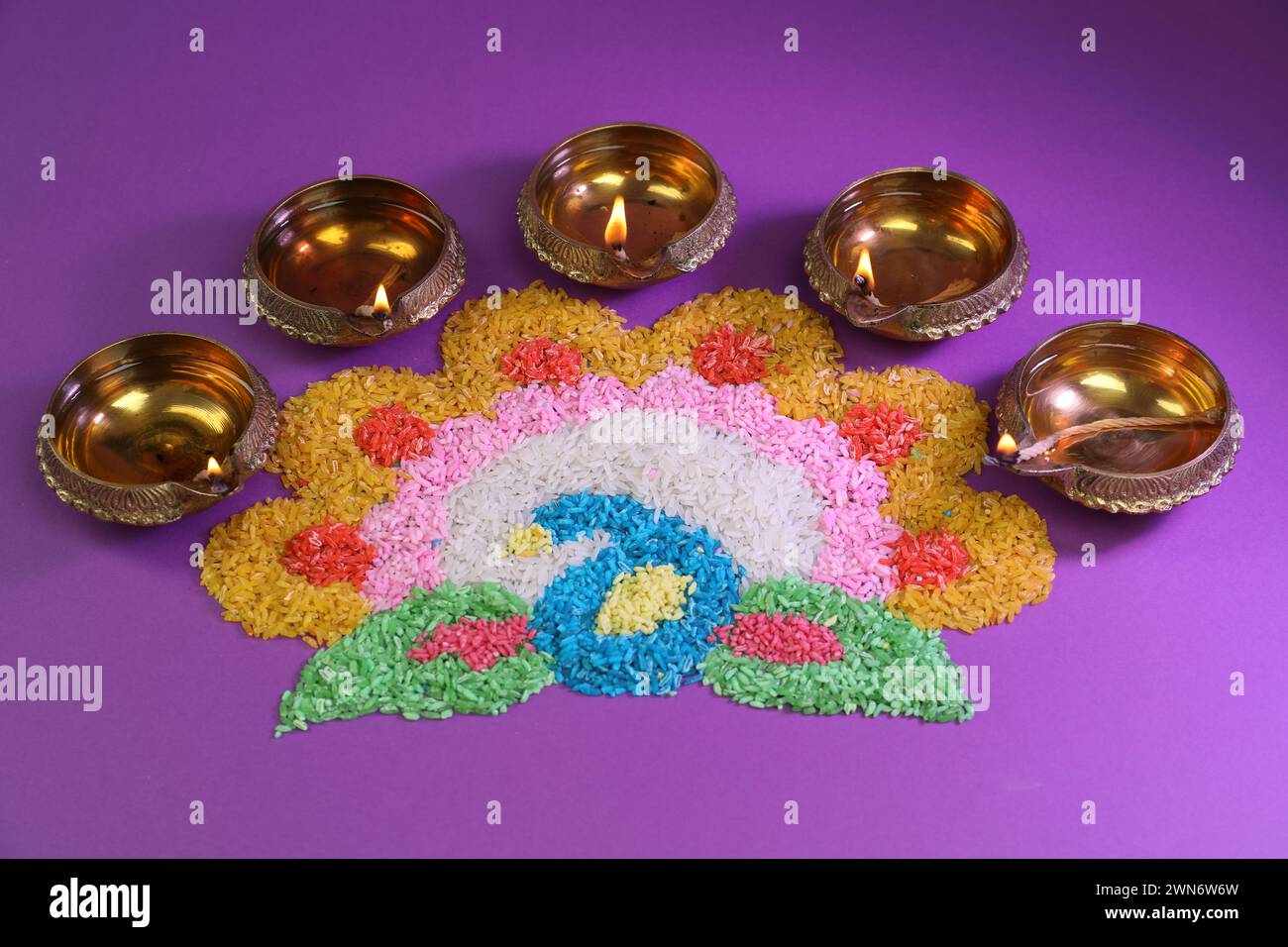 Diwali celebration. Diya lamps and colorful rangoli on purple ...