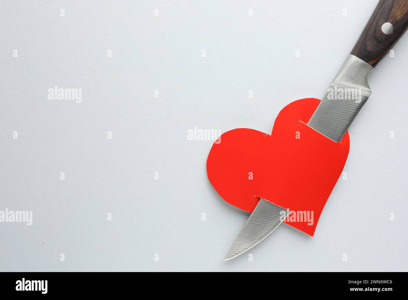 Broken heart. Red paper heart pierced with knife on white background ...