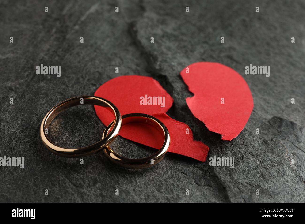 Halves of torn red paper heart and wedding rings on dark grey table. Broken heart Stock Photo ...
