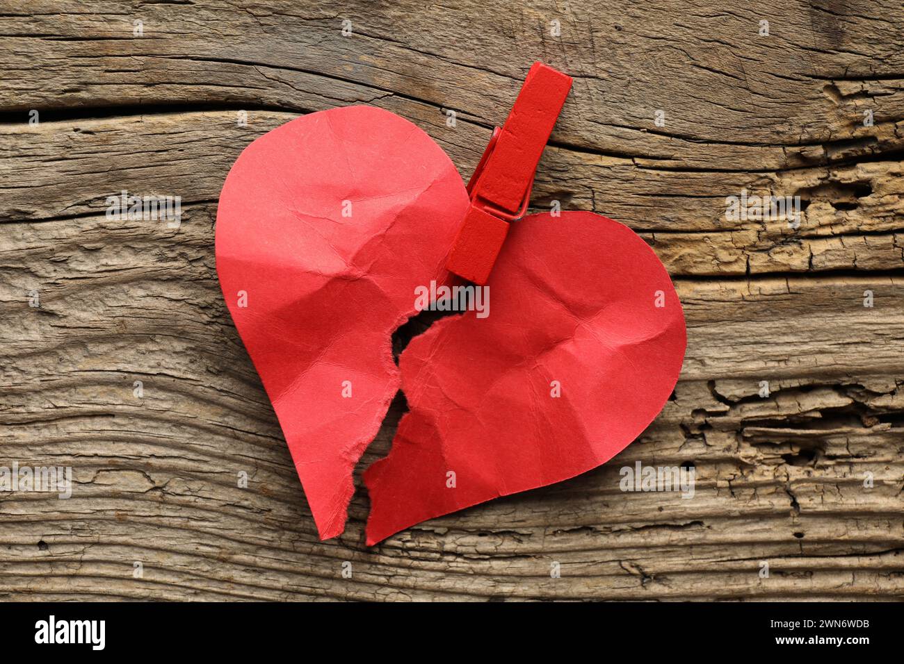 Broken heart. Torn red paper heart with clothespin on wooden table, top ...