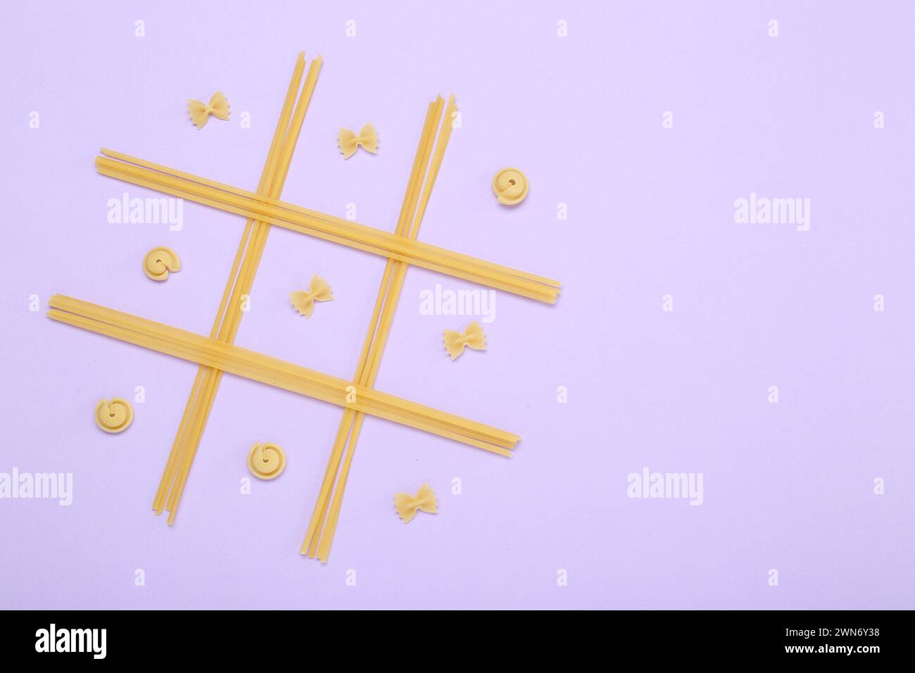 Tic tac toe game made with different types of pasta on lilac background ...
