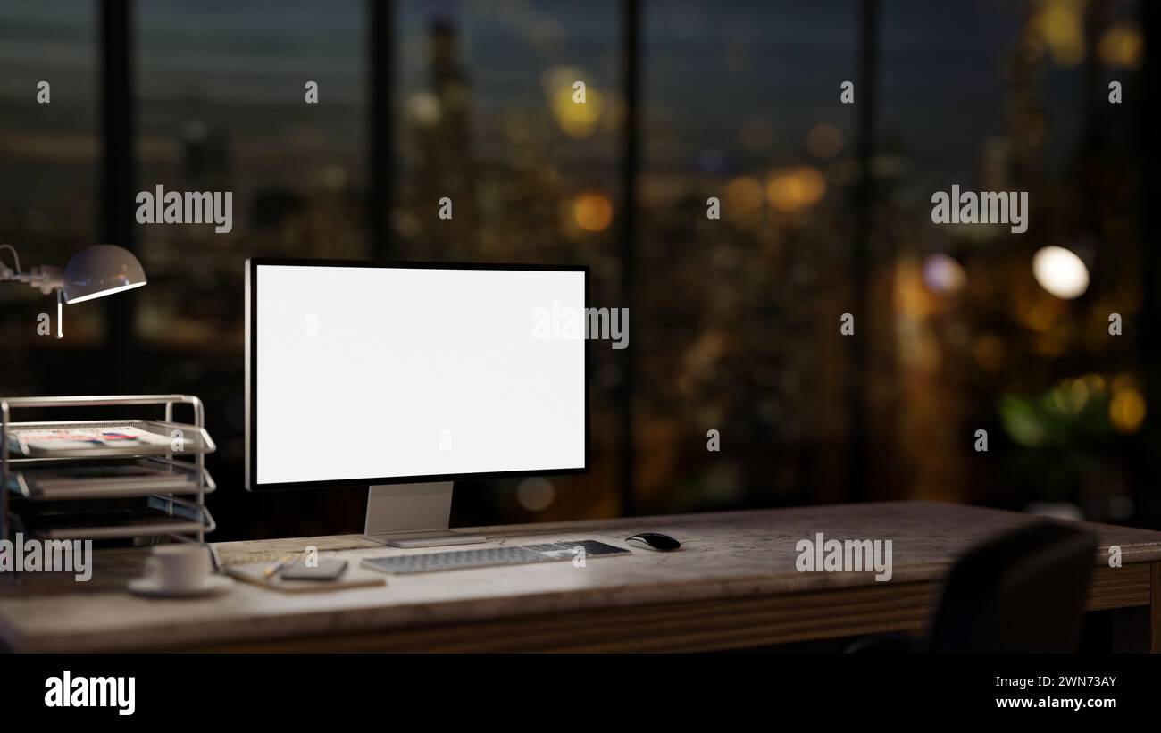 A computer desk in a modern dark office at night with a city view ...
