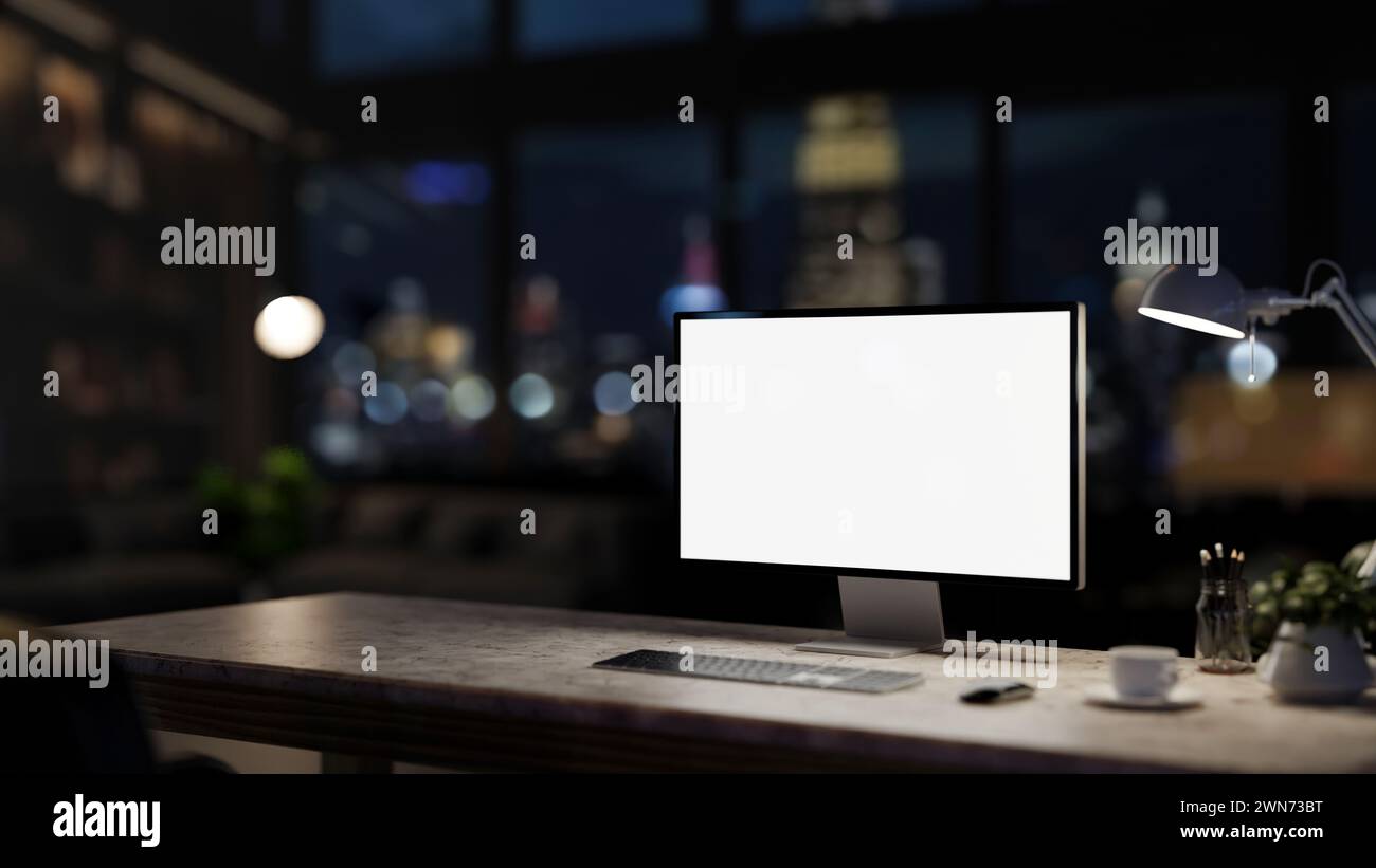 A computer desk in a modern dark office at night with a city view ...