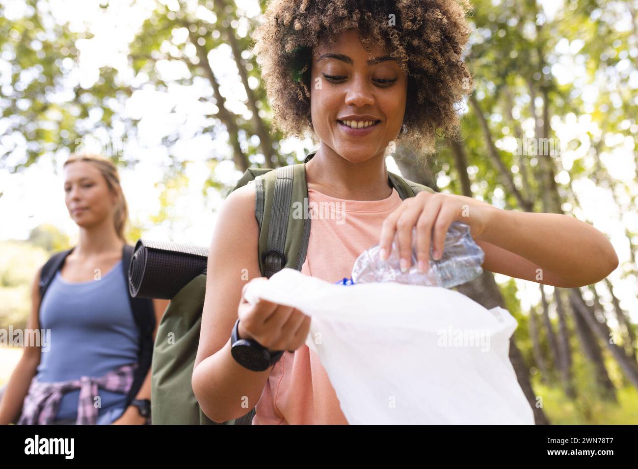 Two women, one biracial, enjoy a hike and collect trash outdoors Stock ...