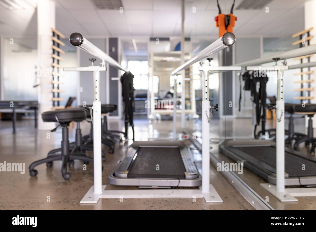 A treadmill flanked by mobility assistance equipment dominates the ...