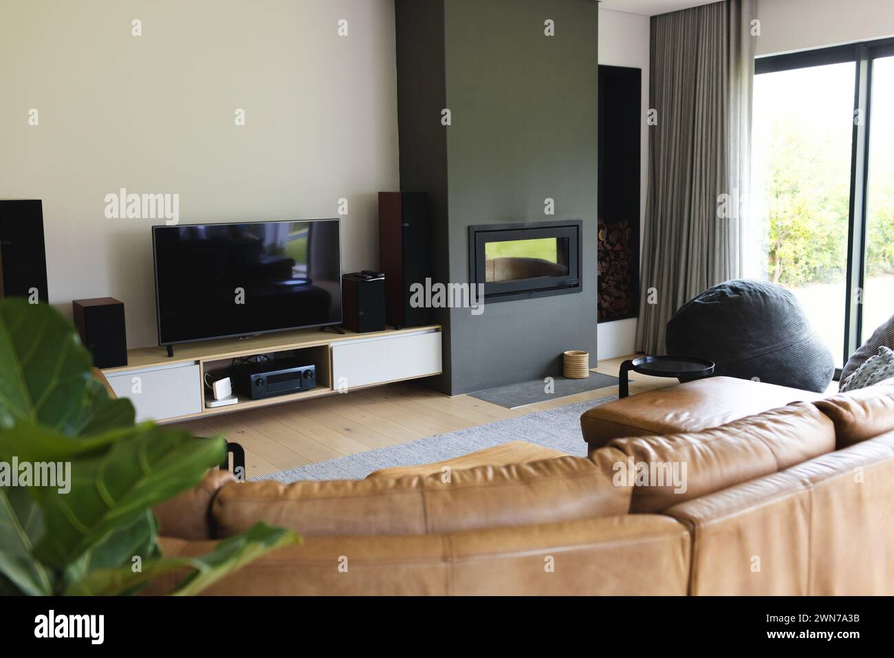 A modern living room features a large TV, a fireplace, and comfortable ...