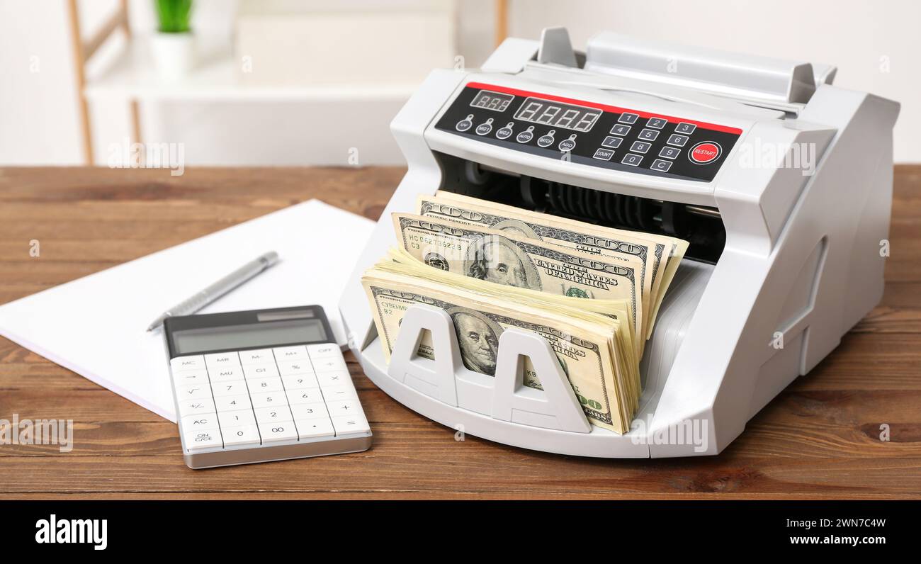 Modern cash counting machine with dollar banknotes, calculator and ...