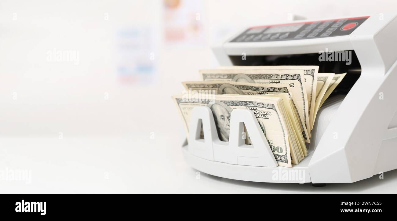 Modern cash counting machine with dollar banknotes on table in office ...