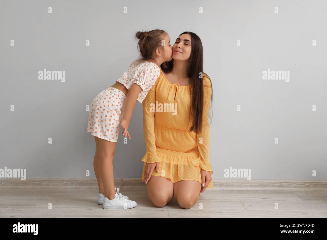Little cute daughter kissing her happy mother near white wall Stock ...