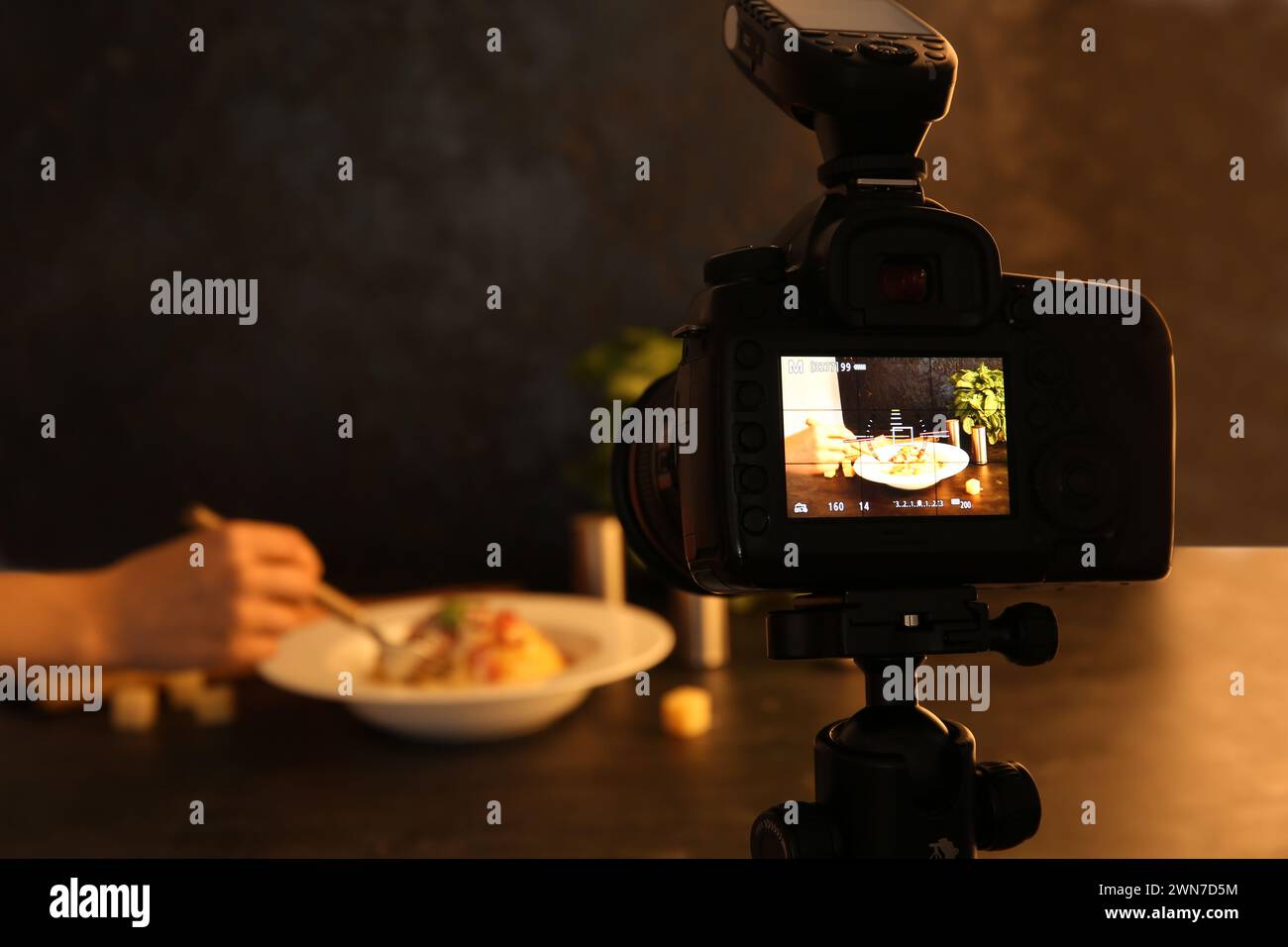 Woman eating restaurant food on display of professional photo camera in ...