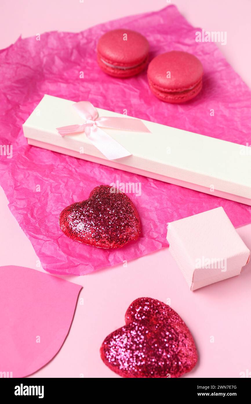Beautiful gift boxes with paper heart and tasty macaroon on pink ...