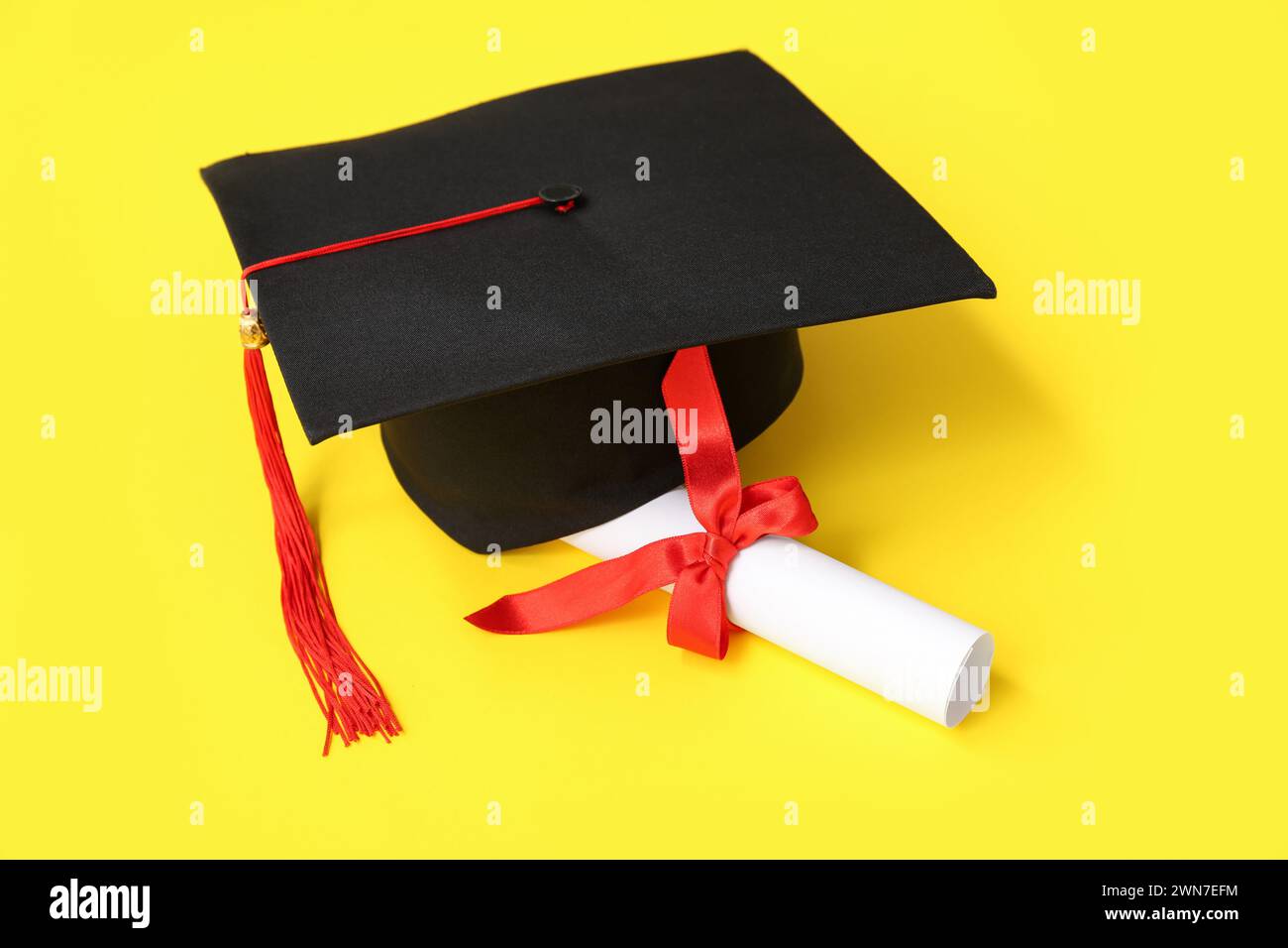 Graduation hat and diploma on yellow background Stock Photo - Alamy