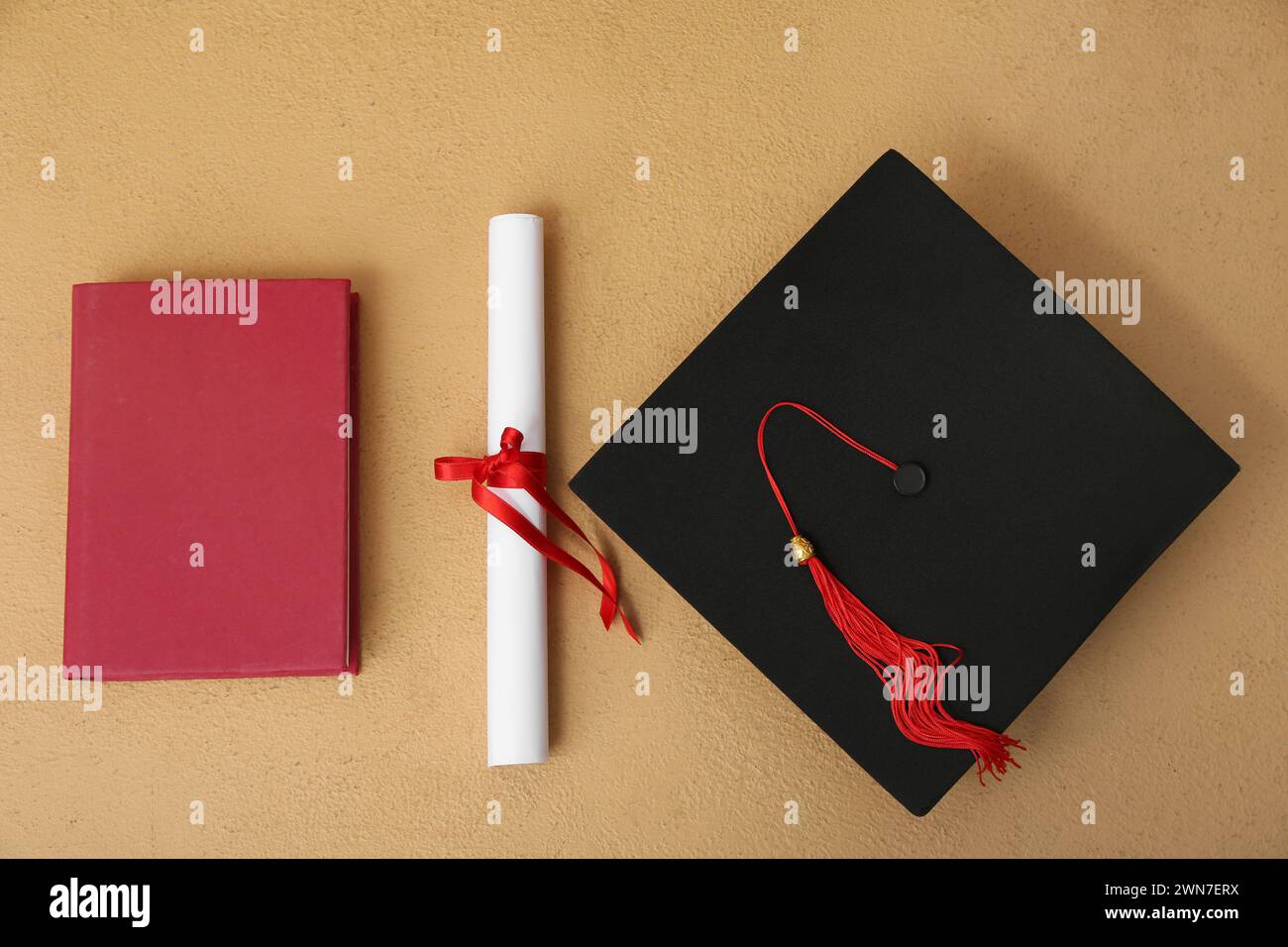 Mortar board with diploma and book on brown background Stock Photo - Alamy