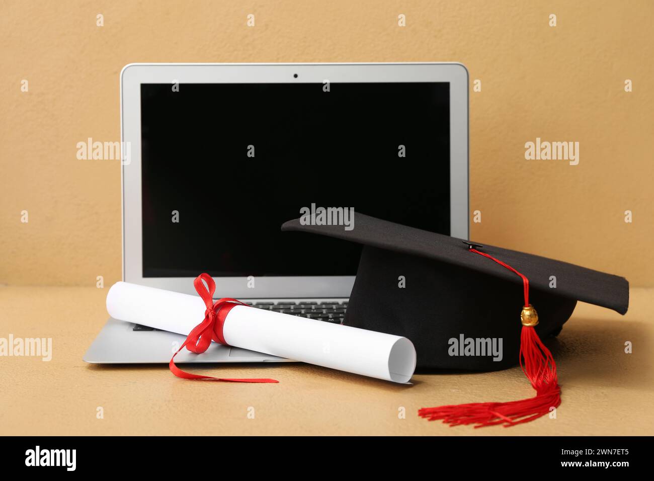 Mortar board with diploma and modern laptop on brown background Stock ...