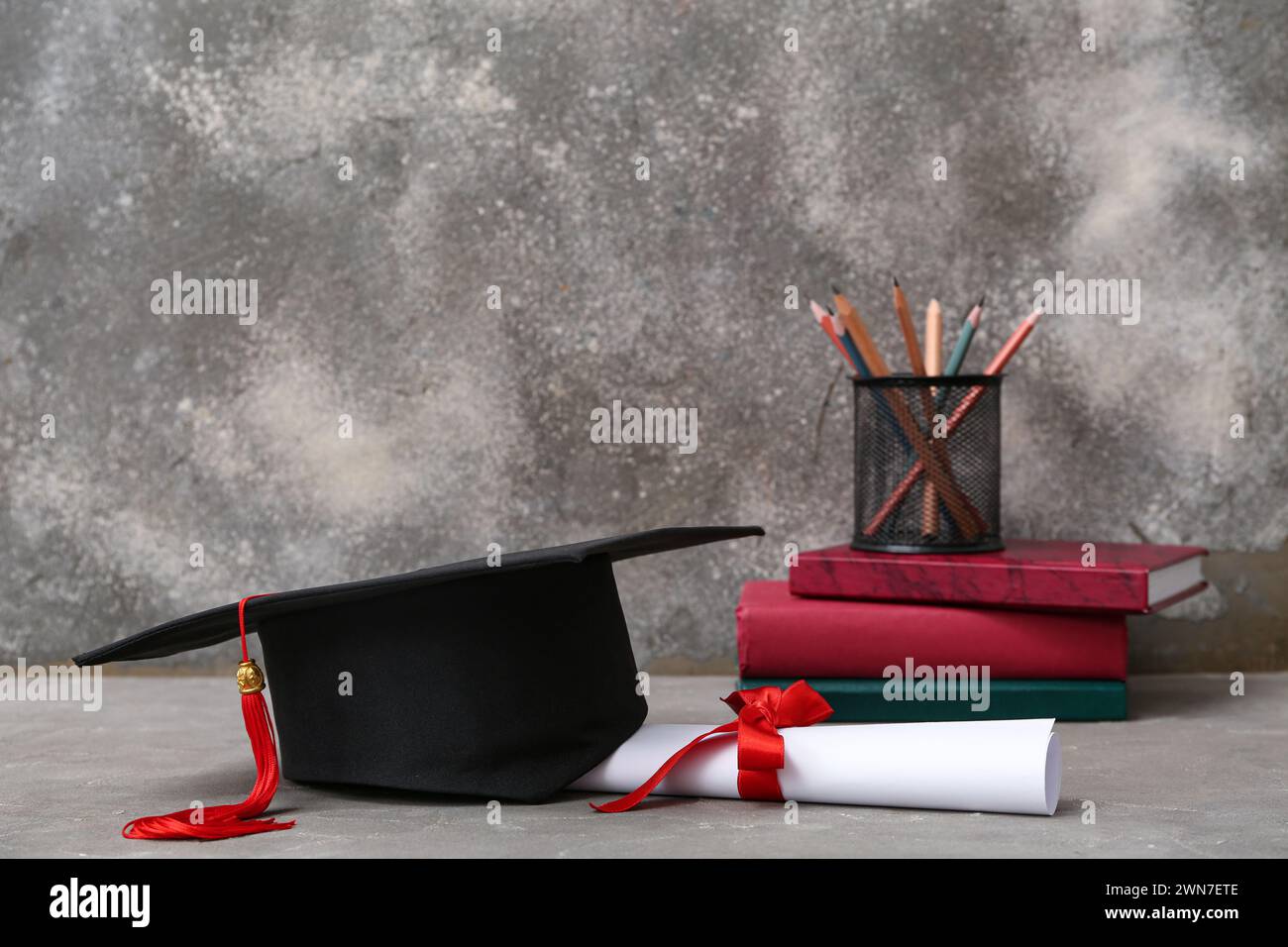 Mortar board with diploma, books and pencils on grey background Stock ...