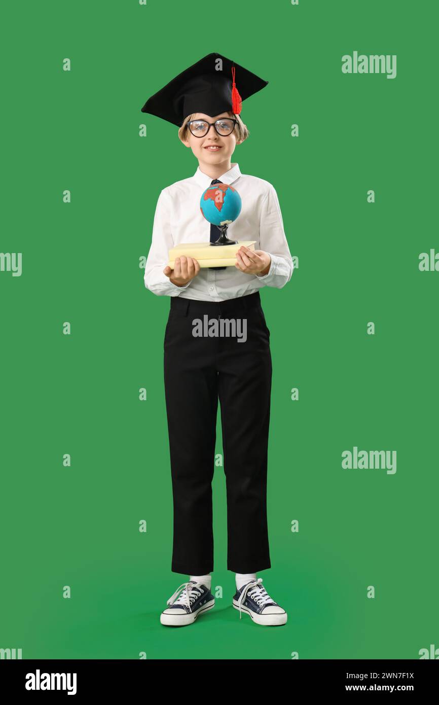 Little boy in graduation hat with globe and books on green background ...