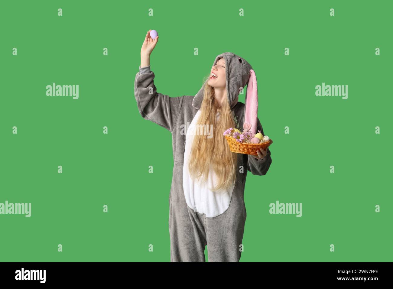 Beautiful young happy woman in bunny costume with basket full of eggs ...