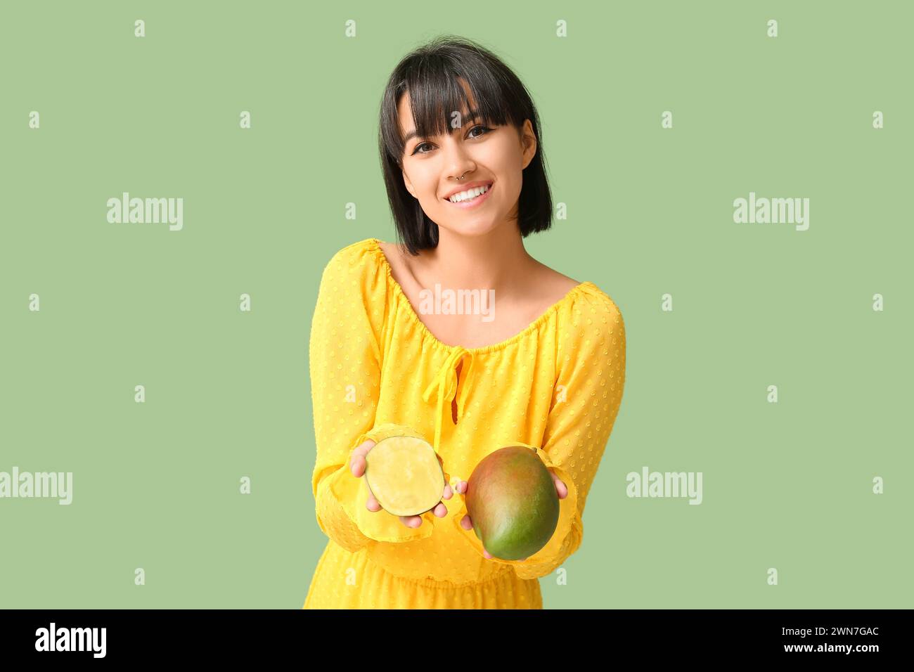 Beautiful young woman with ripe mangoes on green background Stock Photo ...