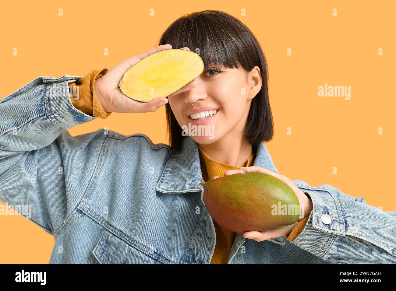 Beautiful young woman with ripe mangoes on yellow background Stock ...