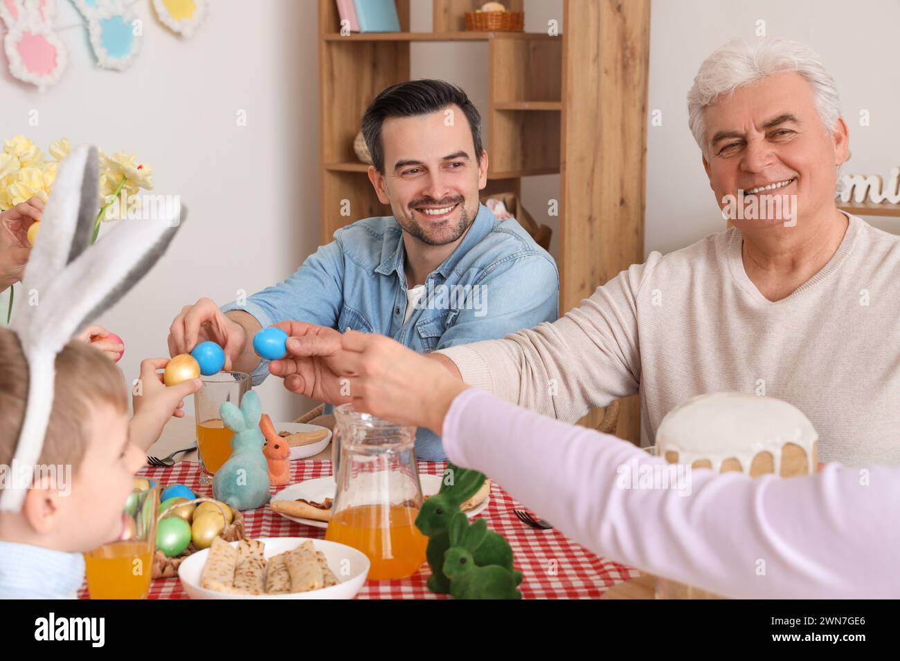 Happy family breaking Easter eggs at home Stock Photo - Alamy