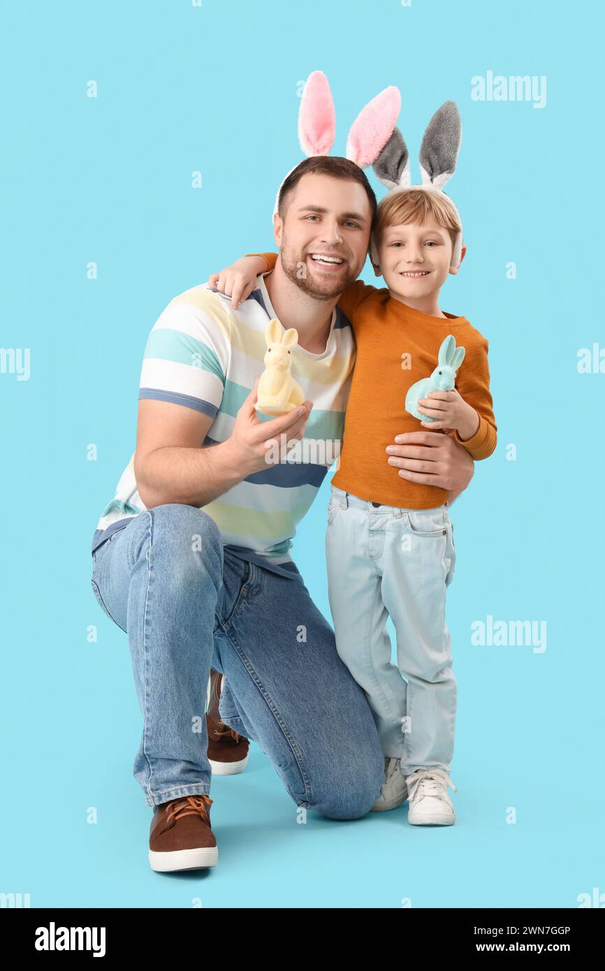 Little boy with his father in bunny ears and Easter rabbits on blue ...