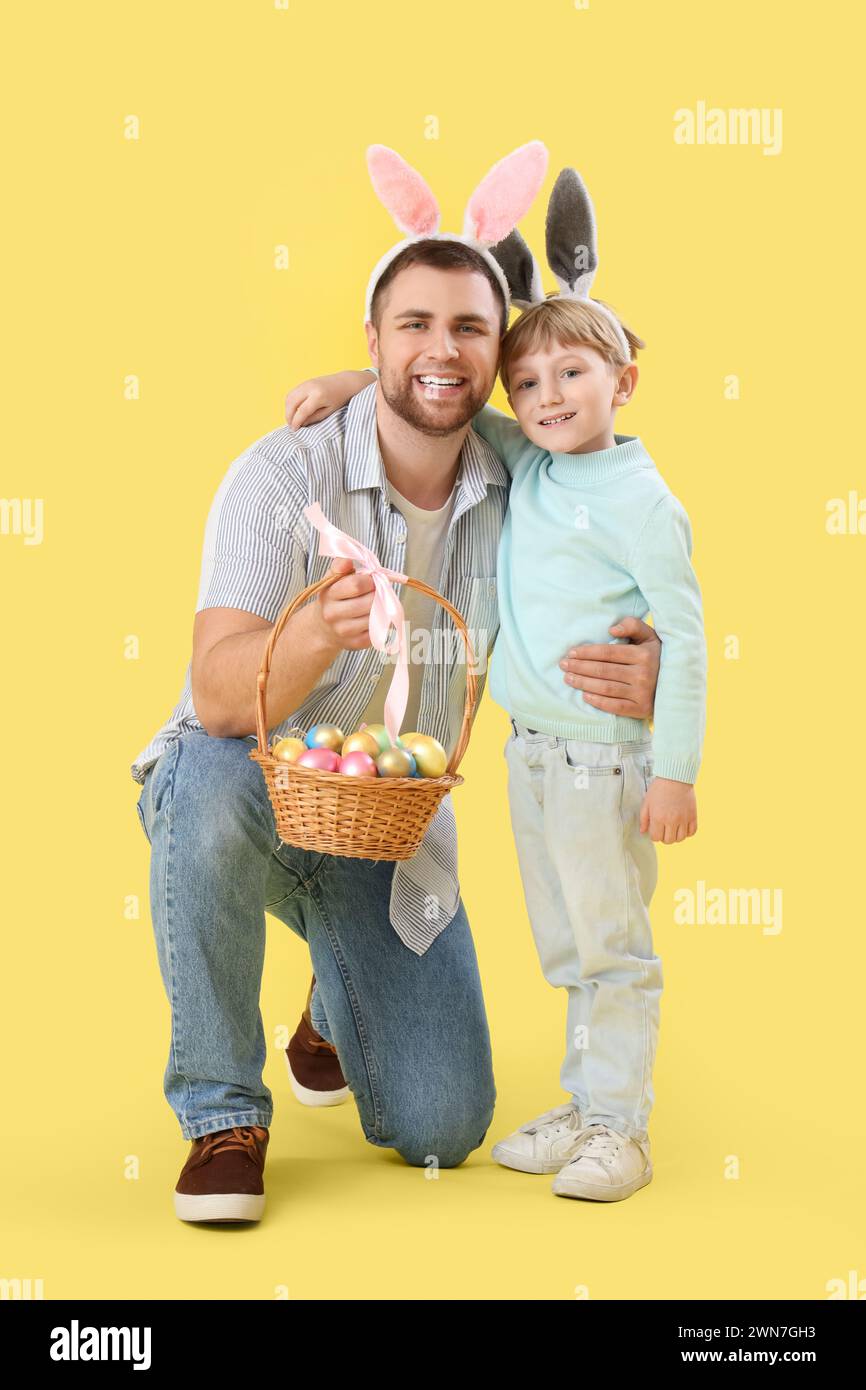 Happy father and his little son in bunny ears with Easter eggs hugging ...