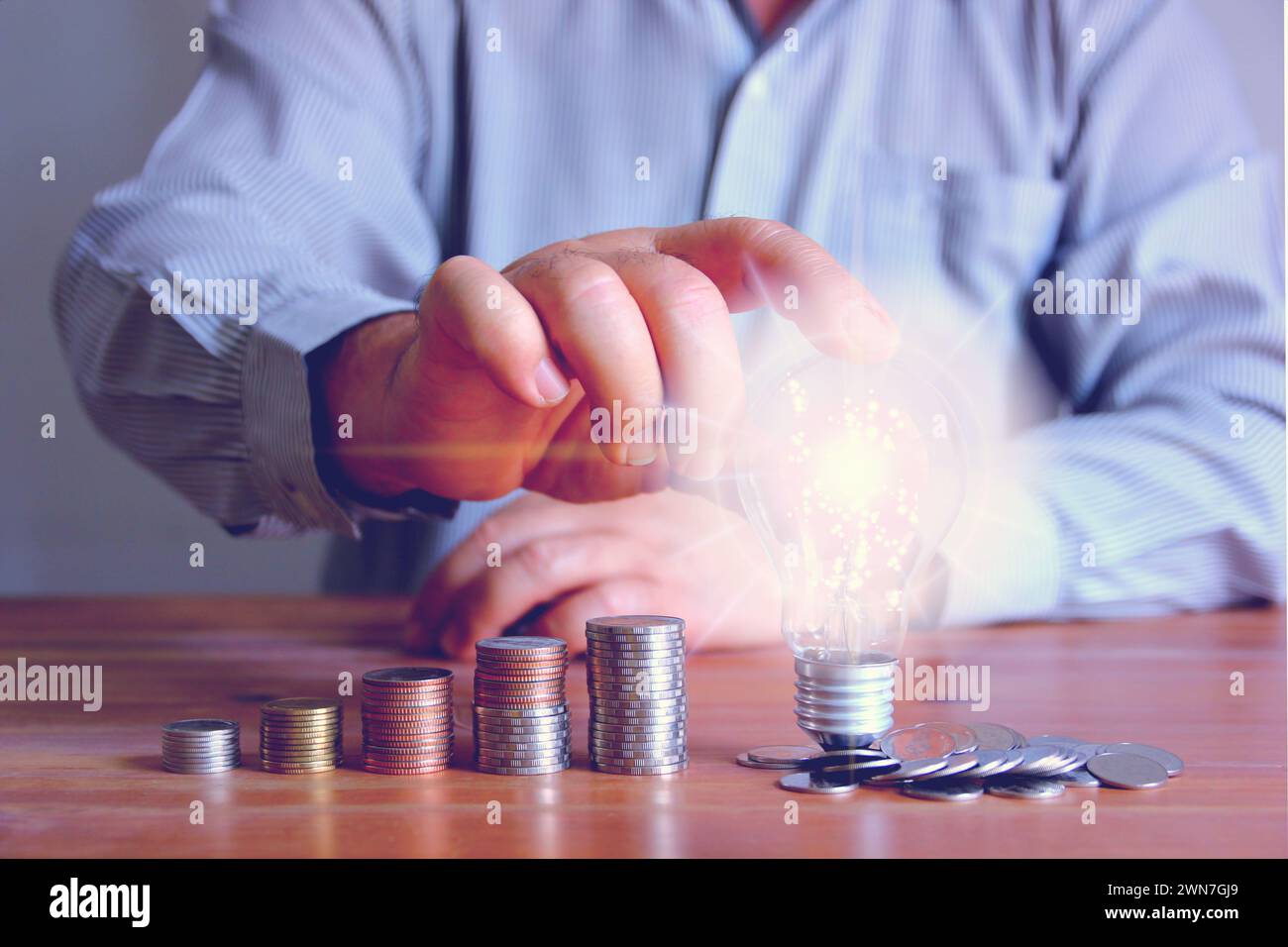 hand holding light bulb shining on group of coin , idea saving concept ...