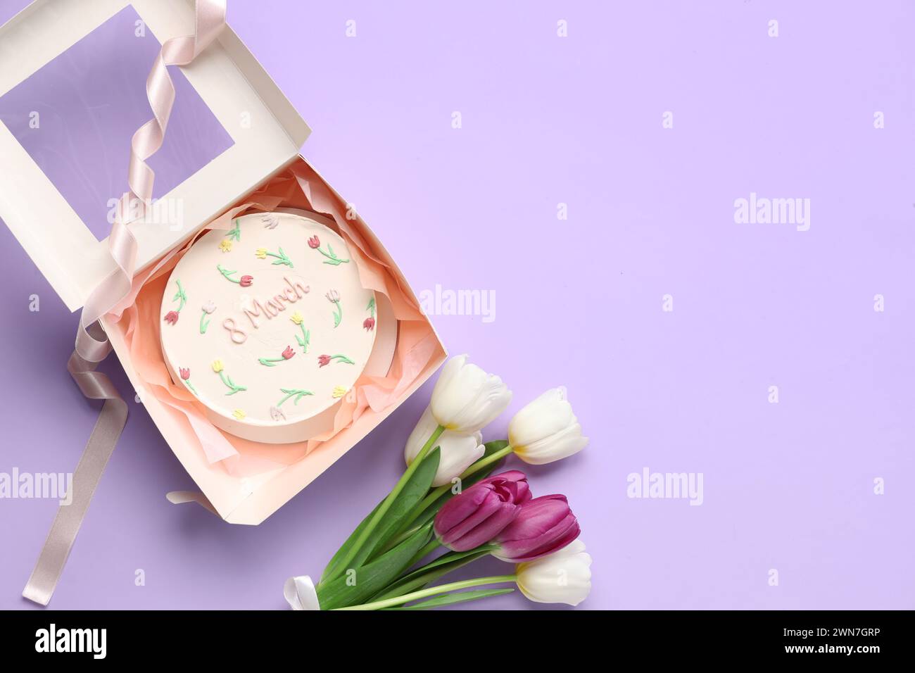 Box with sweet bento cake and bouquet of beautiful tulips on lilac ...
